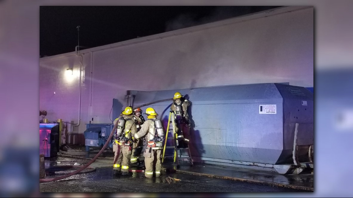 Firefighters respond to a fire in a trash compactor attached to an ...